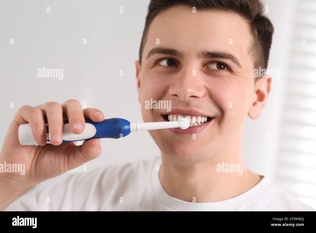 Man brushing his teeth with electric toothbrush indoors Stock Photo - Alamy