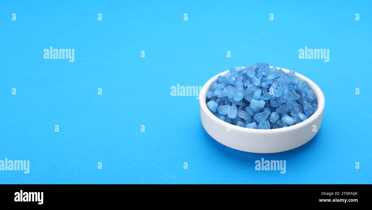 Bowl with aromatic sea salt on light blue background, space for text ...