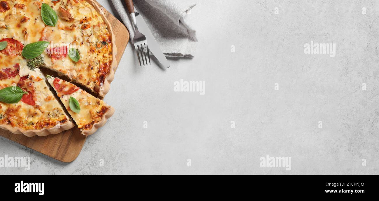 Tasty quiche with tomatoes and cheese served on light textured table ...