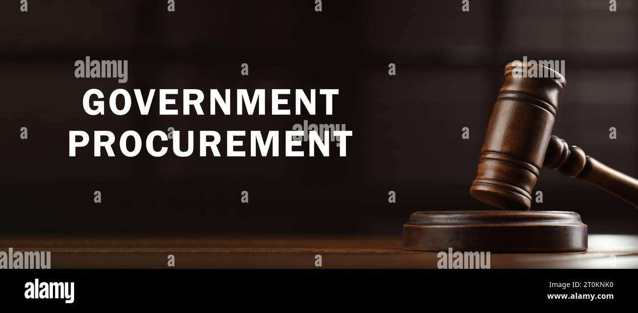 Government procurement. Wooden gavel on table and text against blurred ...