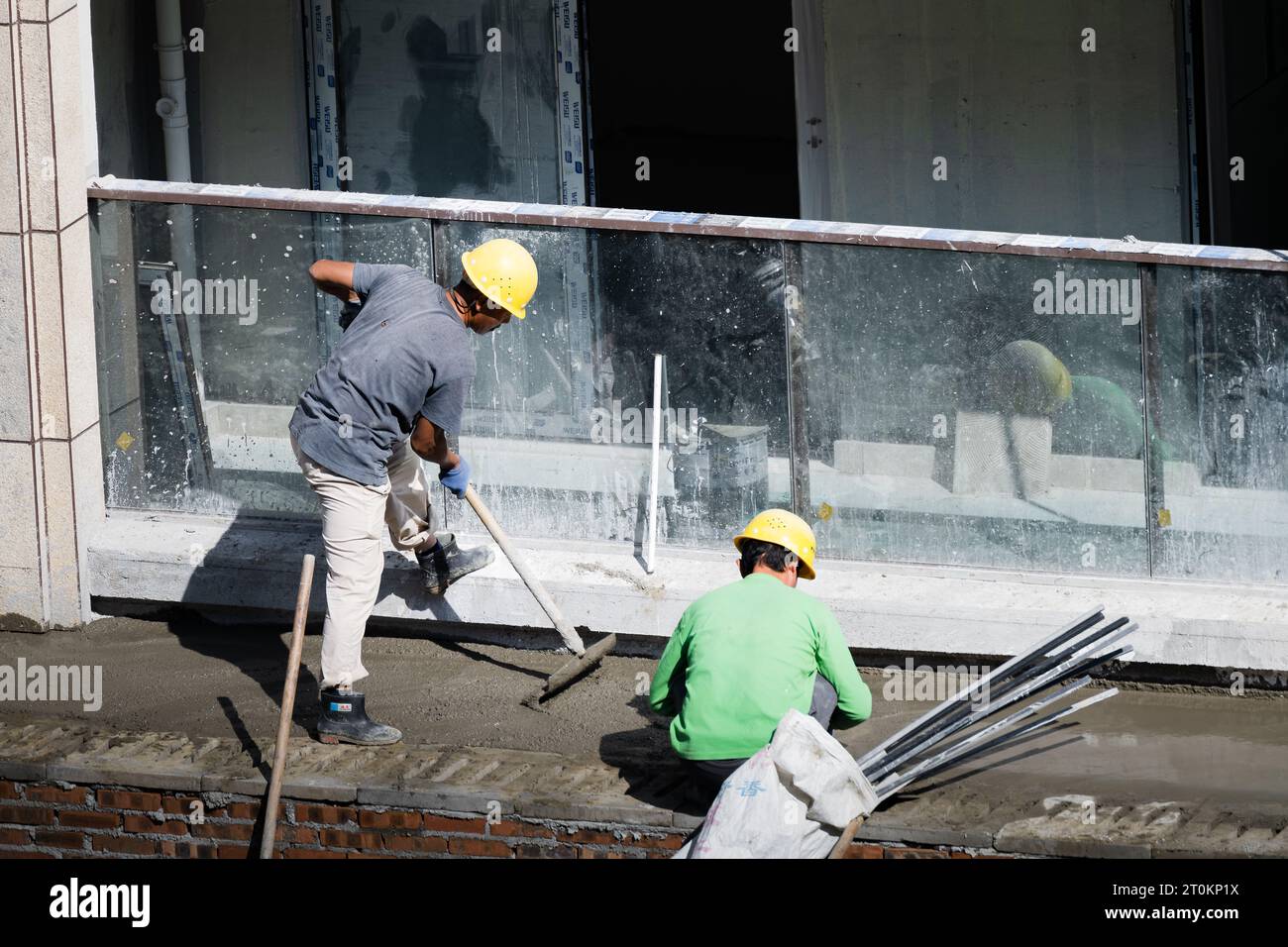 On a sunny day, construction workers are laying cement for the road ...