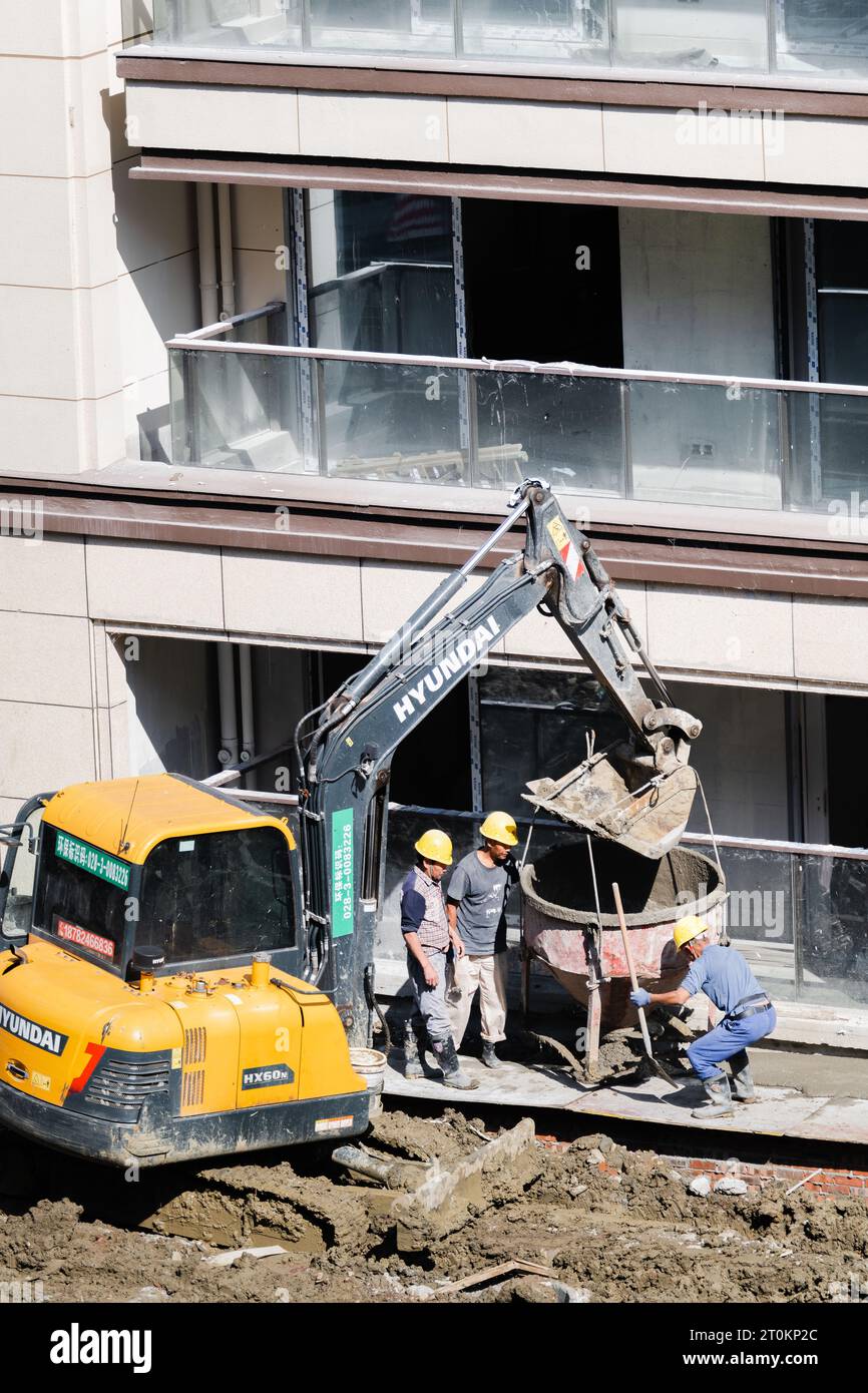 On a sunny day, a group of construction workers is unloading pre-mixed ...