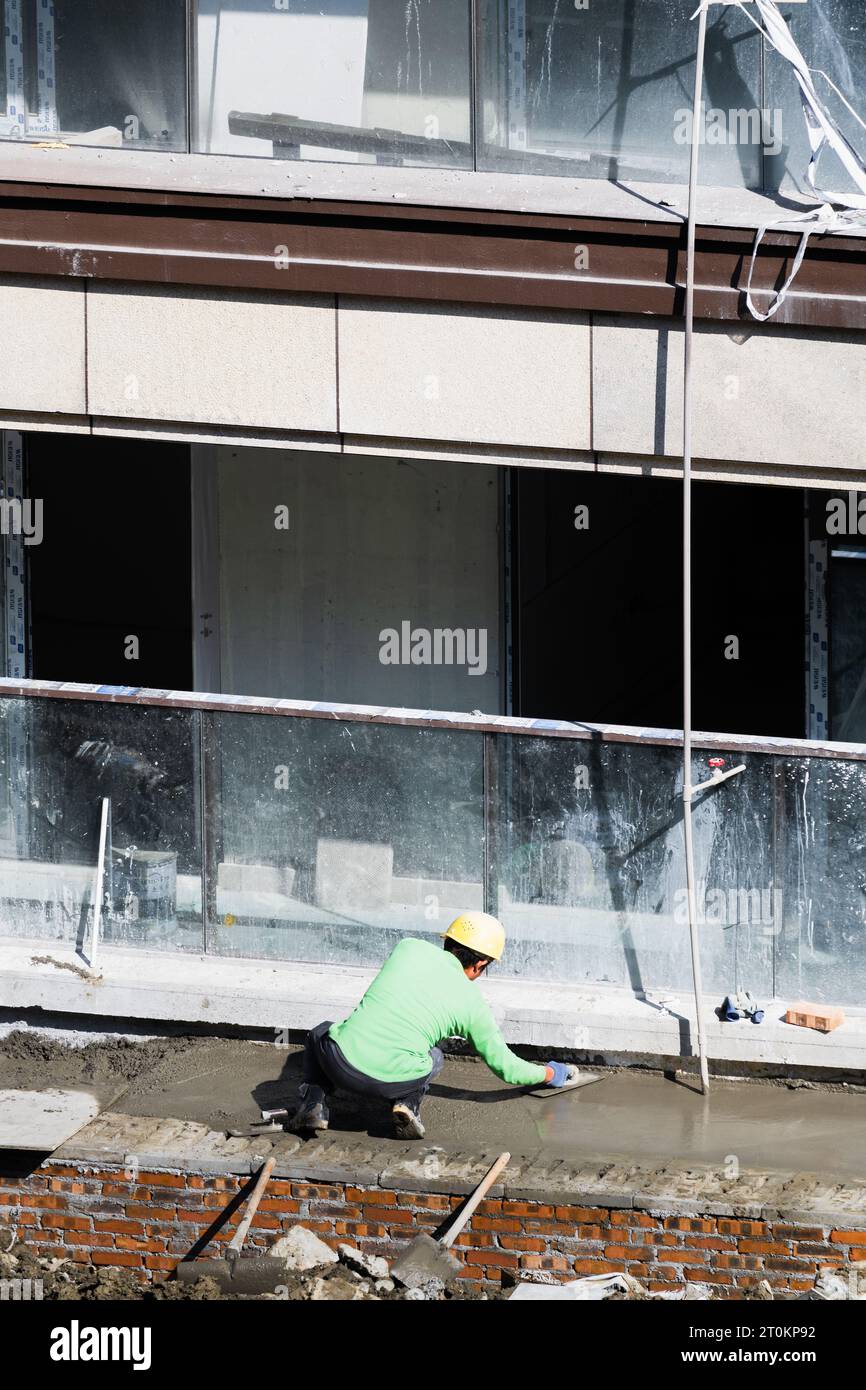 On a sunny day, construction workers are laying cement for the road ...