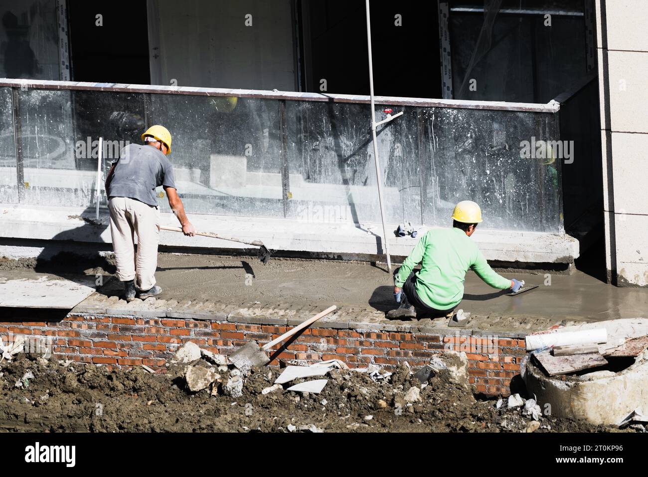 On a sunny day, construction workers are laying cement for the road ...