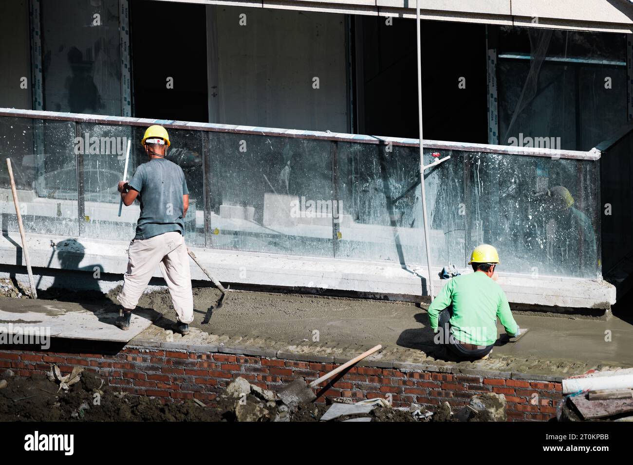 On a sunny day, construction workers are laying cement for the road ...