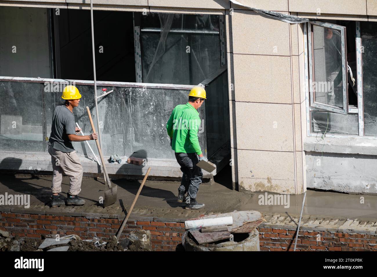 On a sunny day, construction workers are laying cement for the road ...