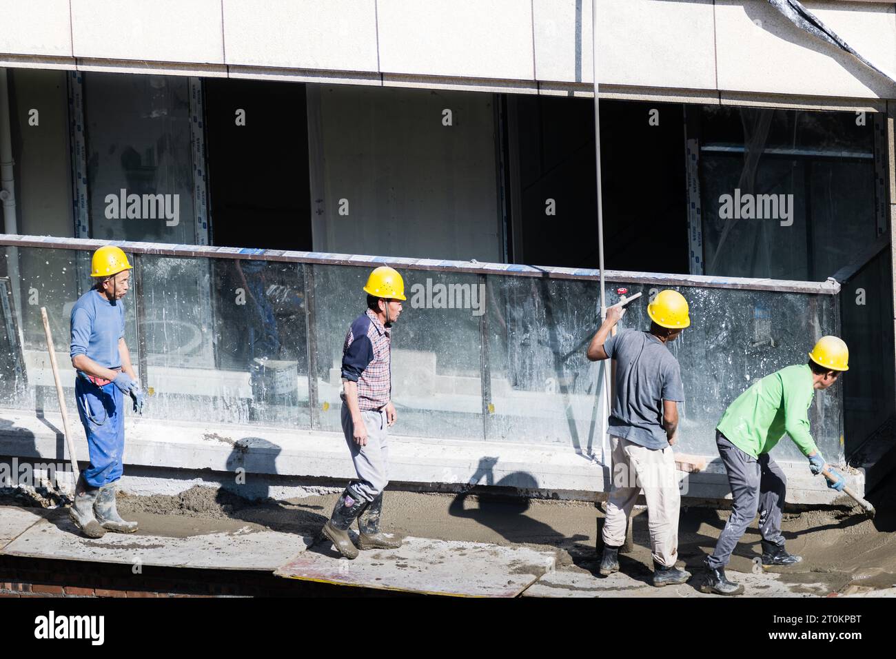 On a sunny day, construction workers are laying cement for the road ...