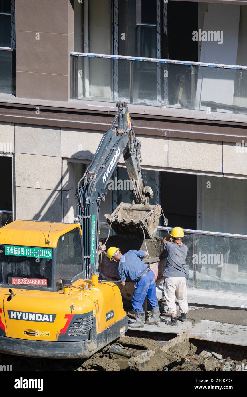 On a sunny day, a group of construction workers is unloading pre-mixed ...