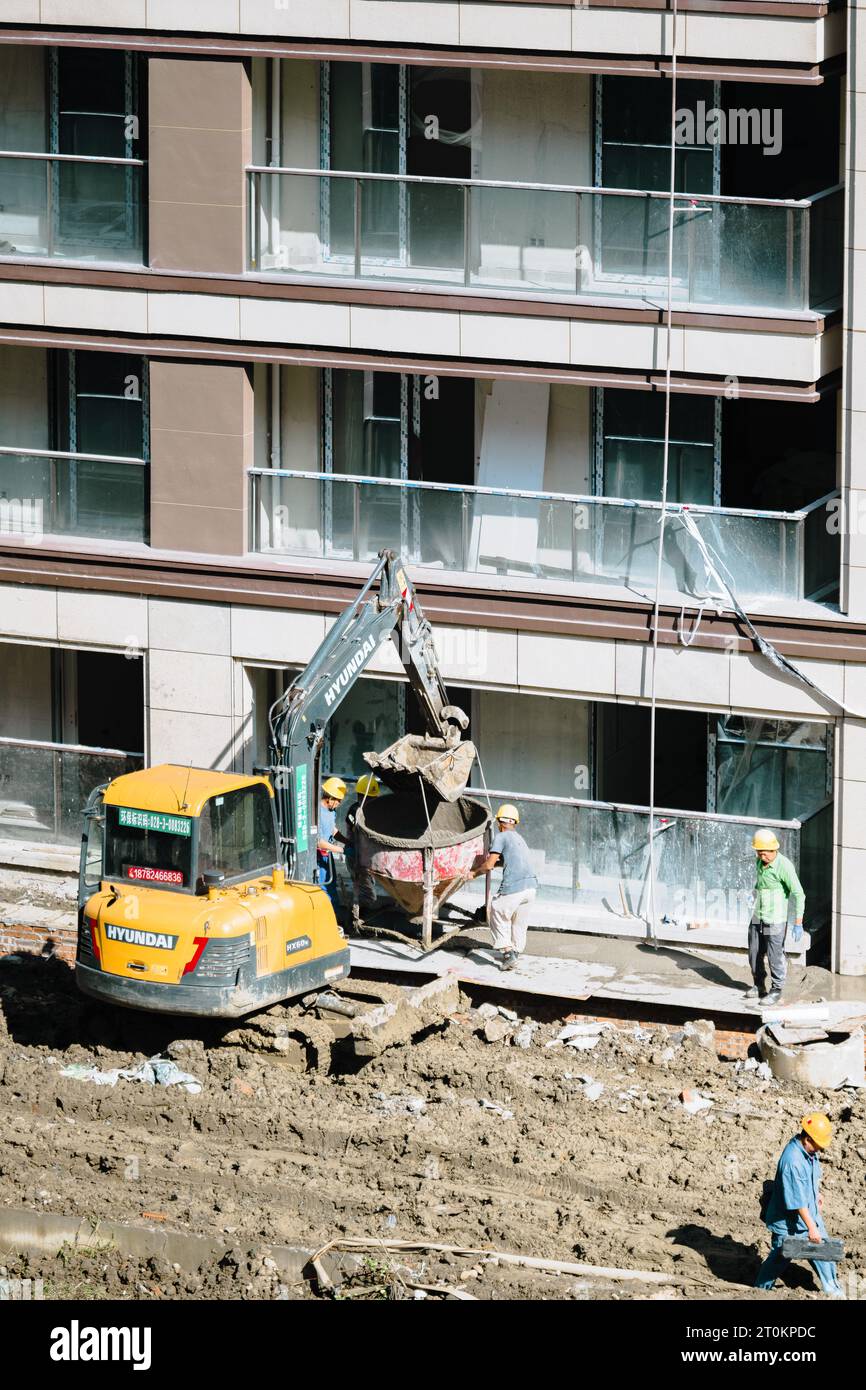 On a sunny day, a group of construction workers is unloading pre-mixed ...