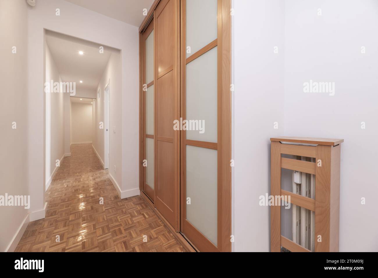 Hallway of a home with a built-in wardrobe with sliding wooden and ...