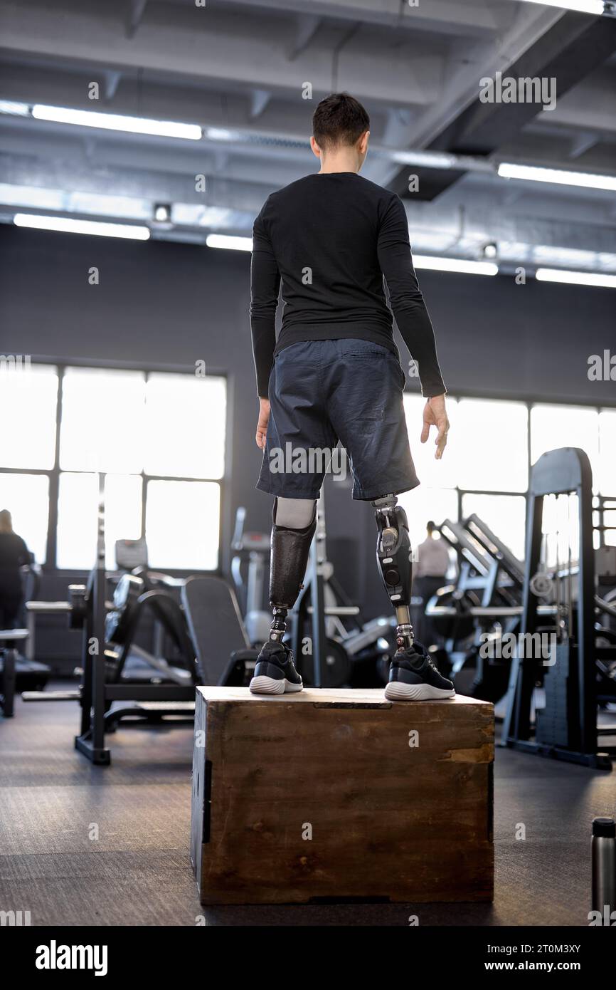 young man with artificial legs going to jump on the floor at gym. cross ...