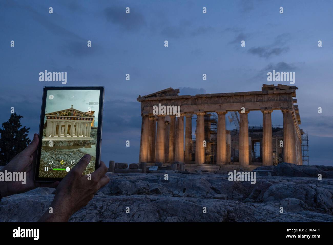 A man holds up a tablet showing a digitally overlayed virtual ...