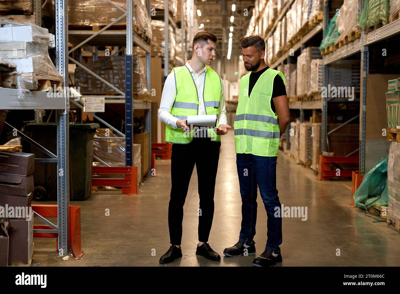 Men warehouse workers talking. holding document paper. two young ...