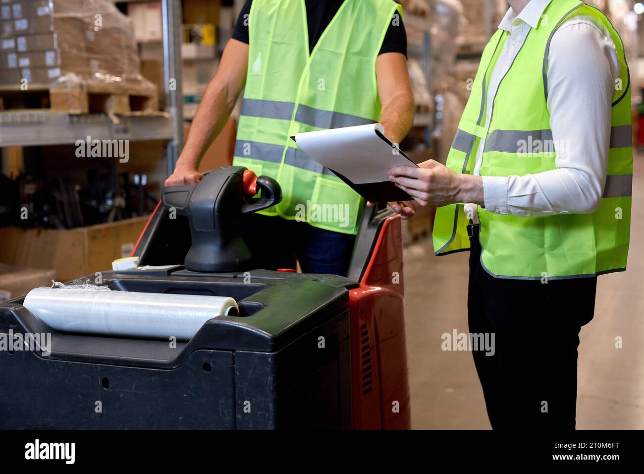 warehouse workers men in reflective jackets pulling a pallet truck and ...