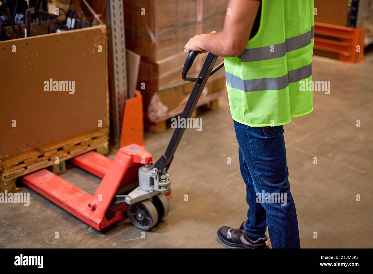 worker in a warehouse uses hand pallet stacker to transport pallets ...