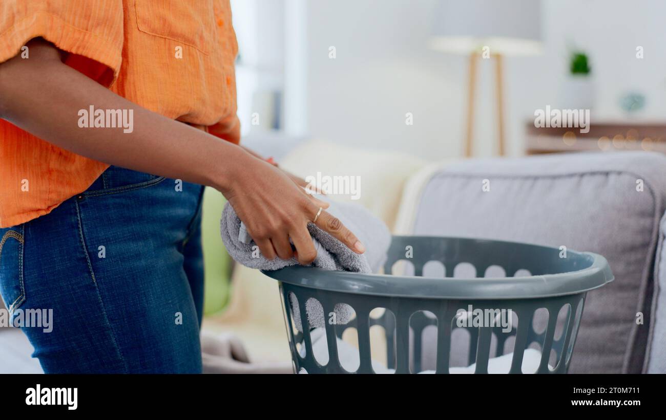 Hands, housework and woman folding laundry in a living room, cleaning and tidy in her home. Hand ...