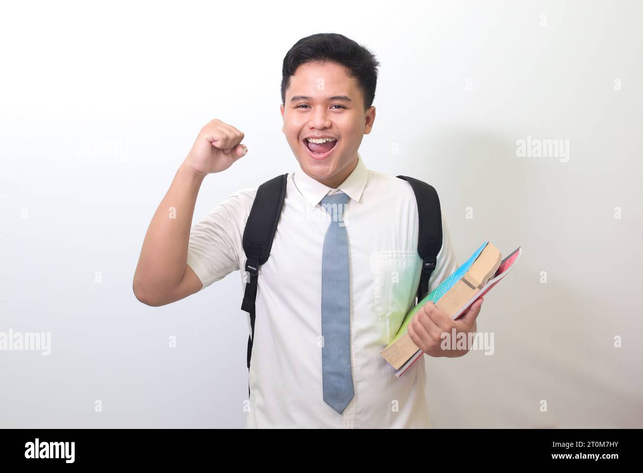 Indonesian senior high school student wearing white shirt uniform with gray tie holding some ...