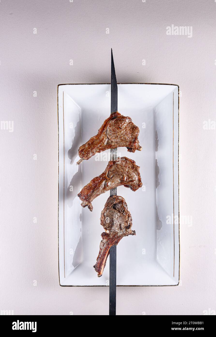 amazing lamb ribs on a skewer on a white plate. . View from above ...