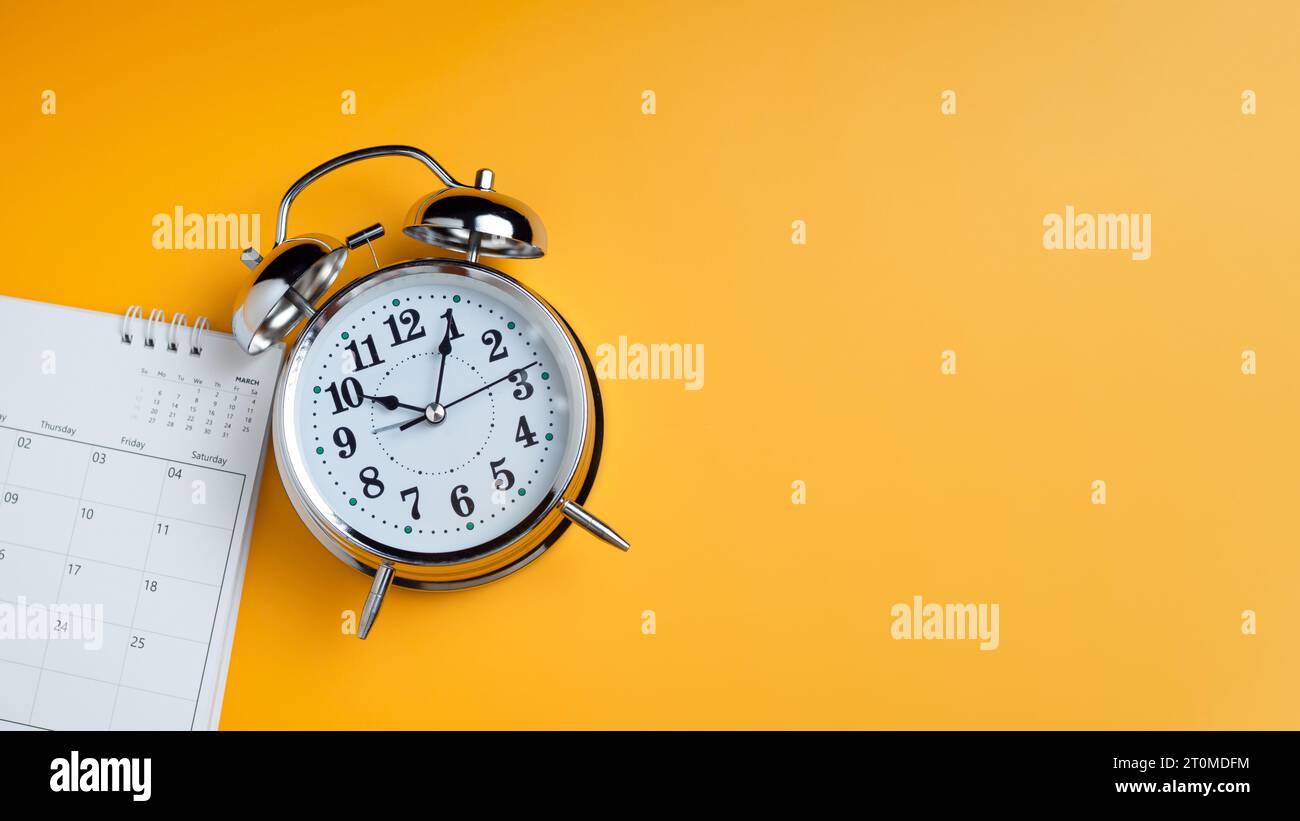 Top view of calendar and alarm clock on yellow background, planning for ...
