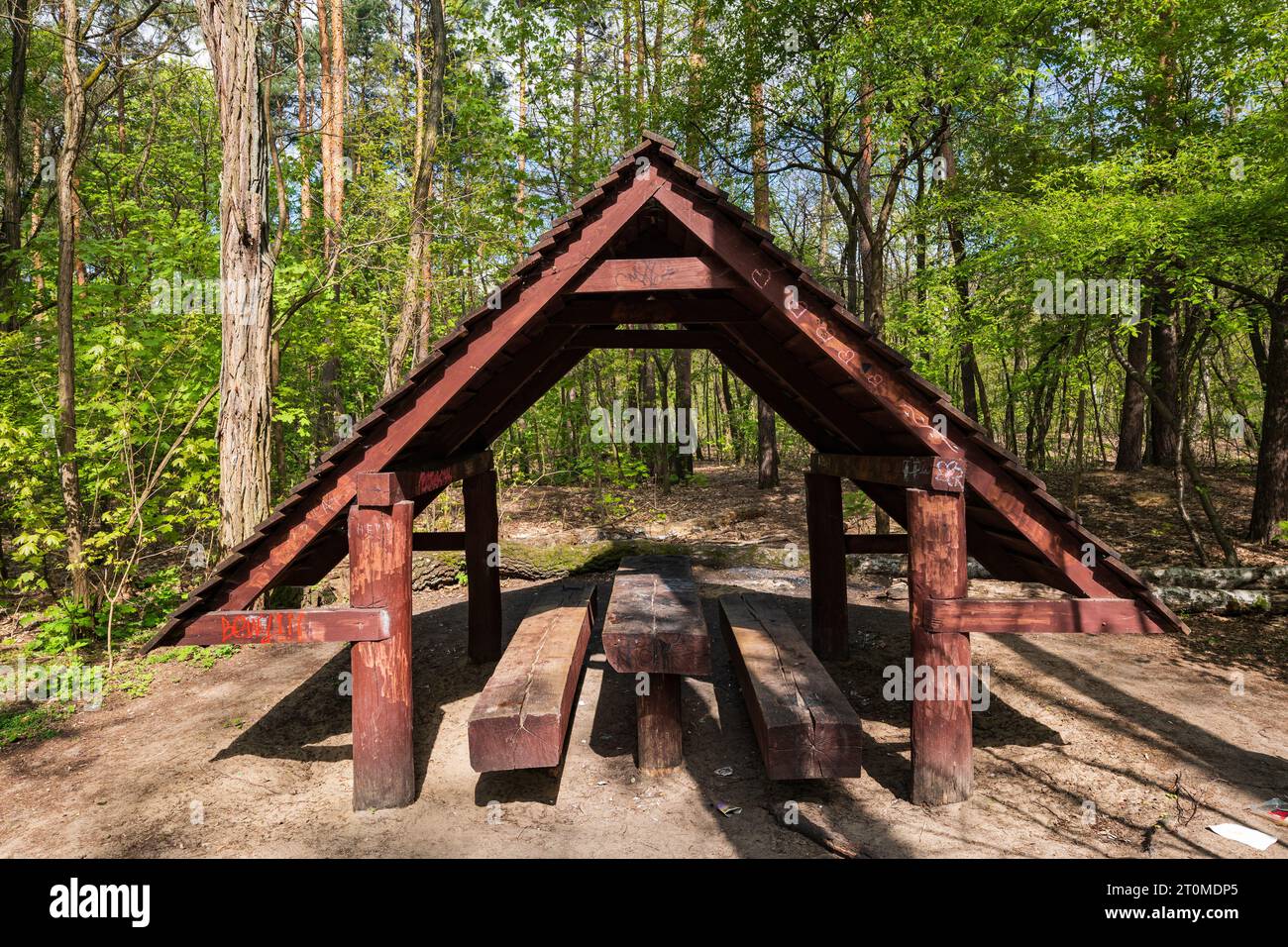 Wooden roofed forest shelter with benches and table, rest area for ...