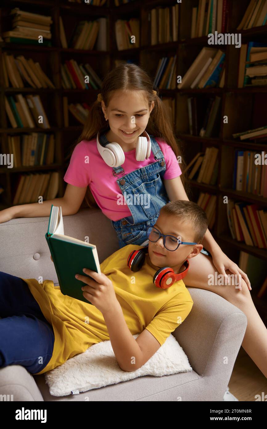 Happy brother and sister reading together at home library preparing for ...