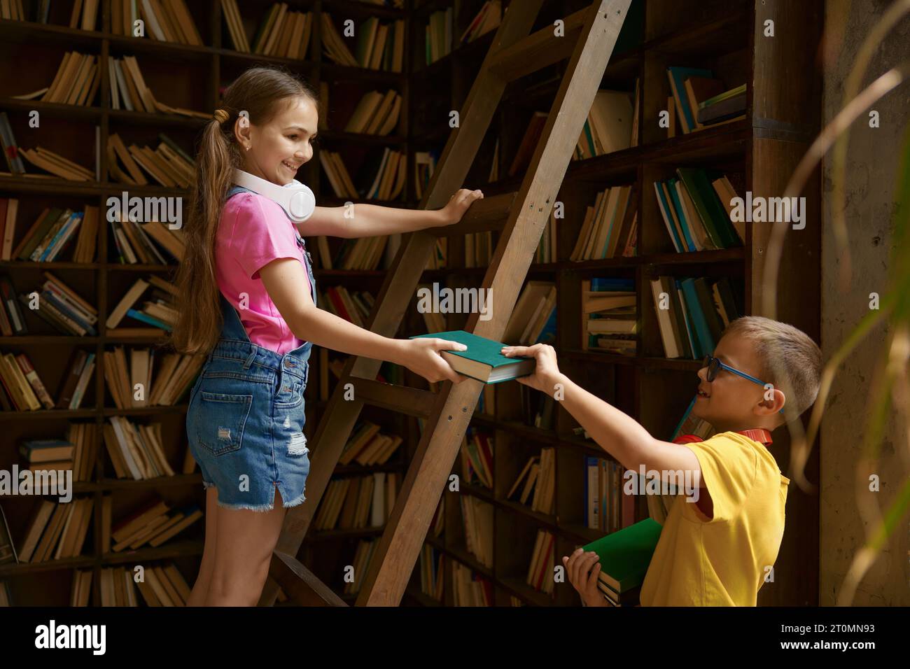 Children being on duty putting away books in home or school library ...