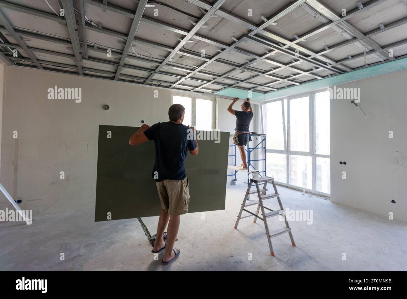 Workers fitting panel into frame of ceiling Stock Photo - Alamy