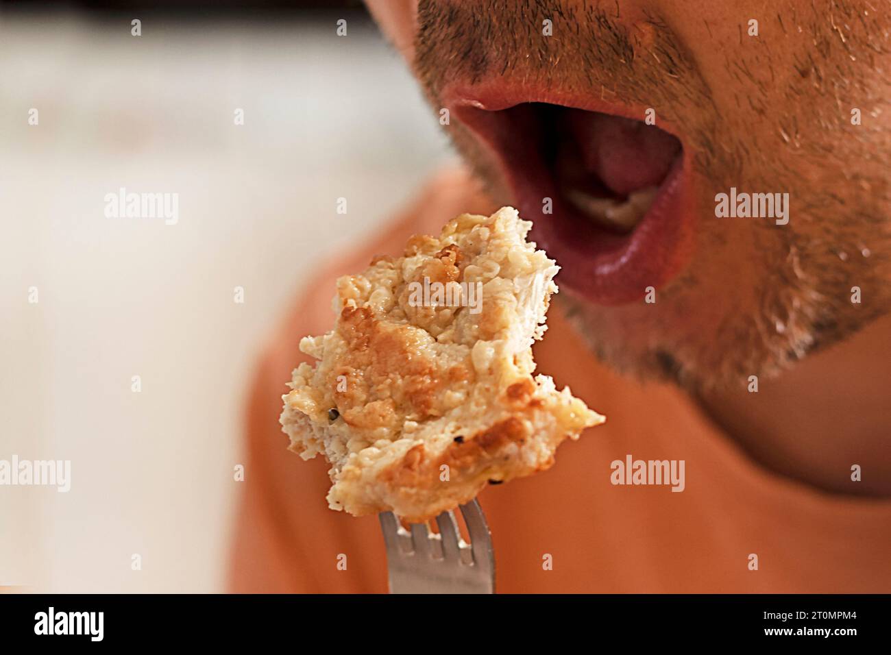 close-up of a man opening his mouth to eat a piece of fried chicken ...