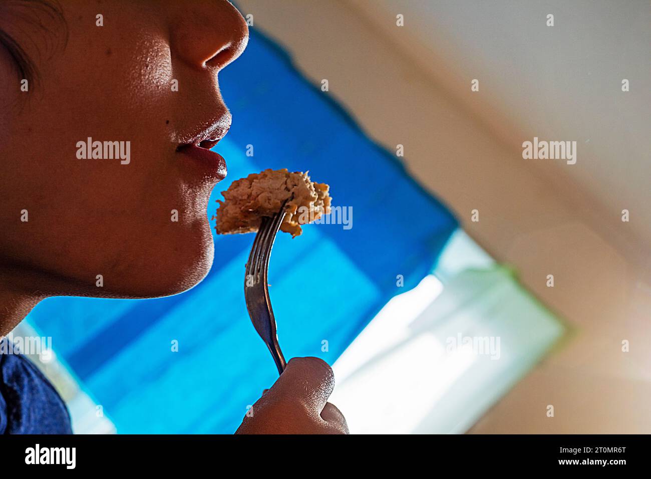 boy's face in profile holding a piece of meat on a fork Stock Photo - Alamy