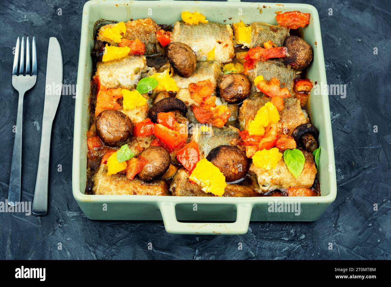 Baked hake fish with orange, tomato and mushrooms. Seafood roasted in ...