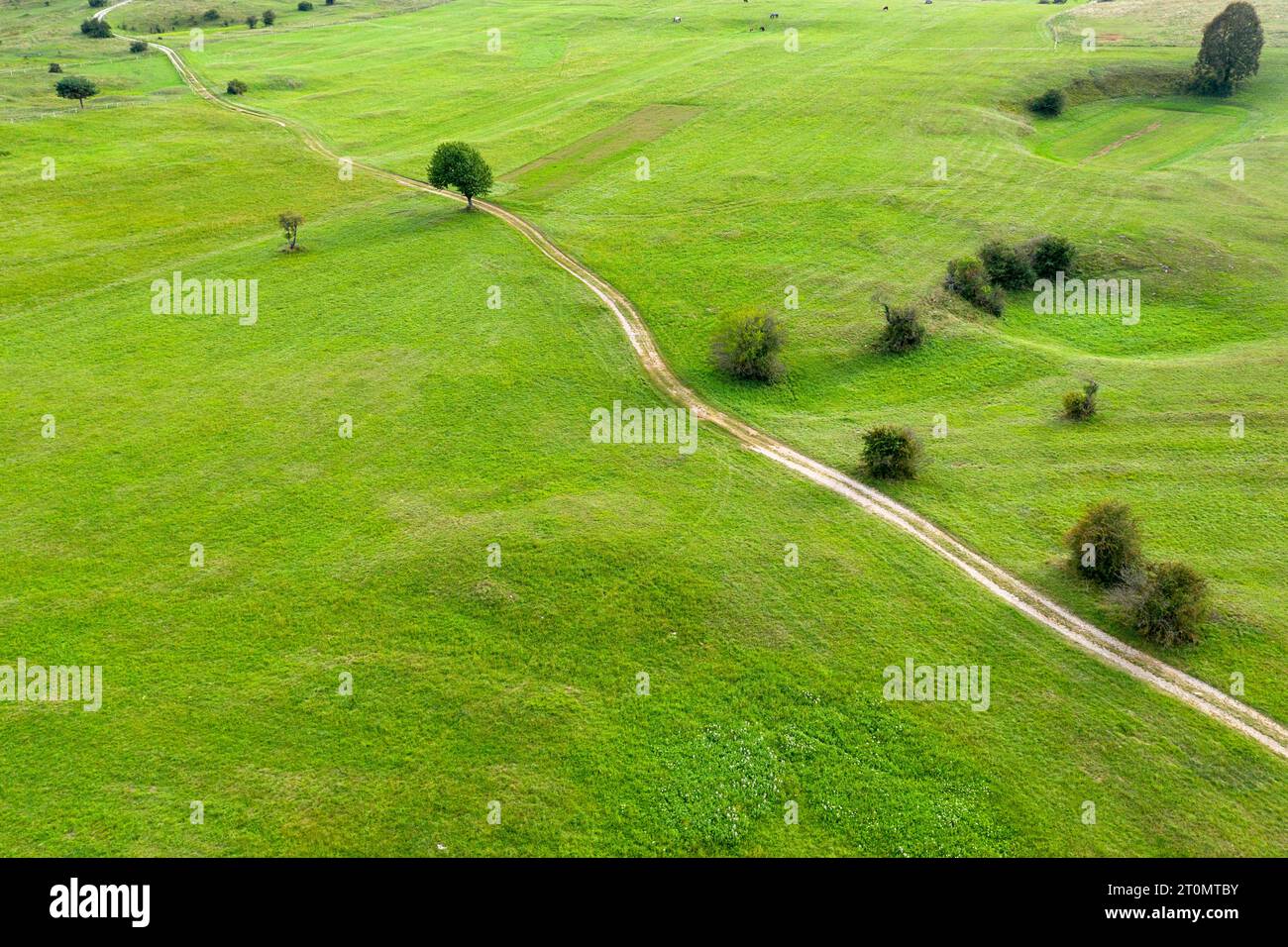 Aerial view of a gravel road passing lush green hilly karst countryside ...
