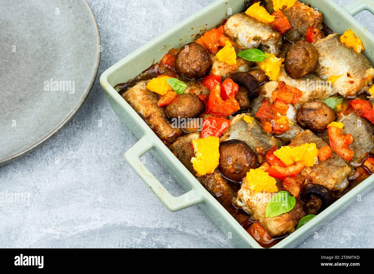 Diet fish hake cooked with mushrooms, orange and tomatoes. White fish ...