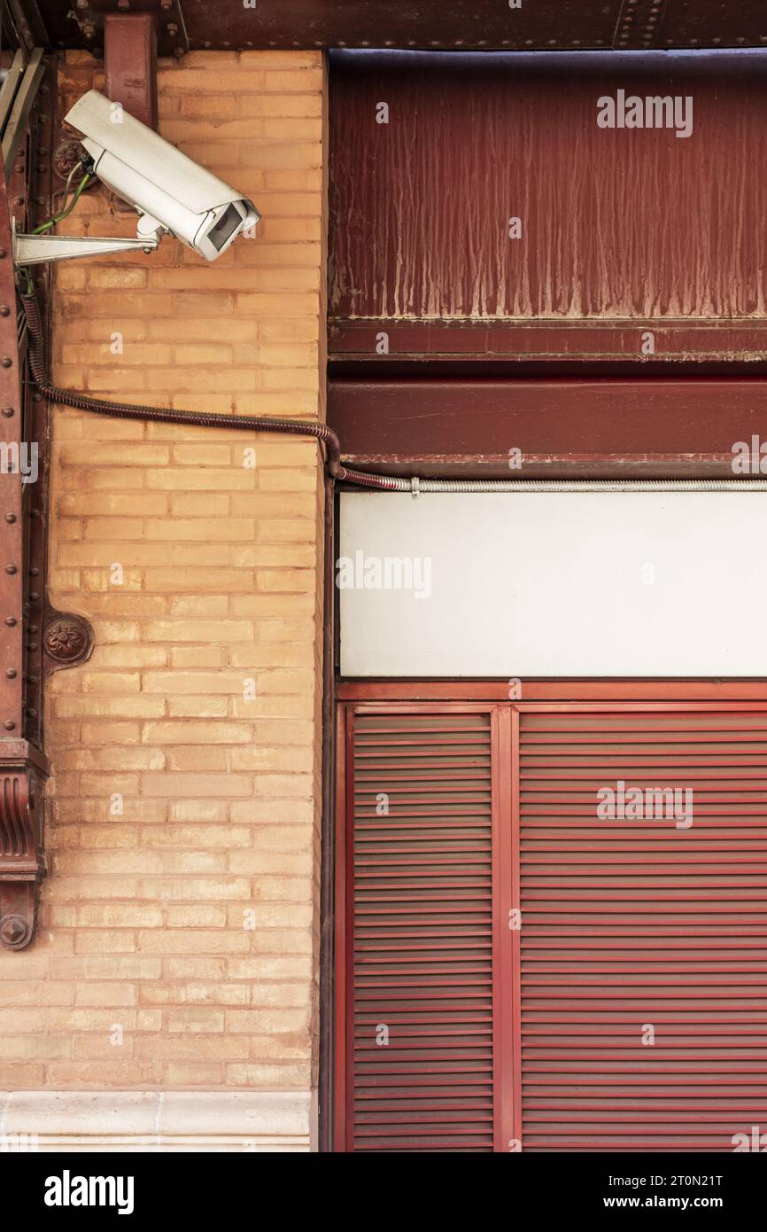 Surveillance camera hanging on the wall of a building with clay brick ...