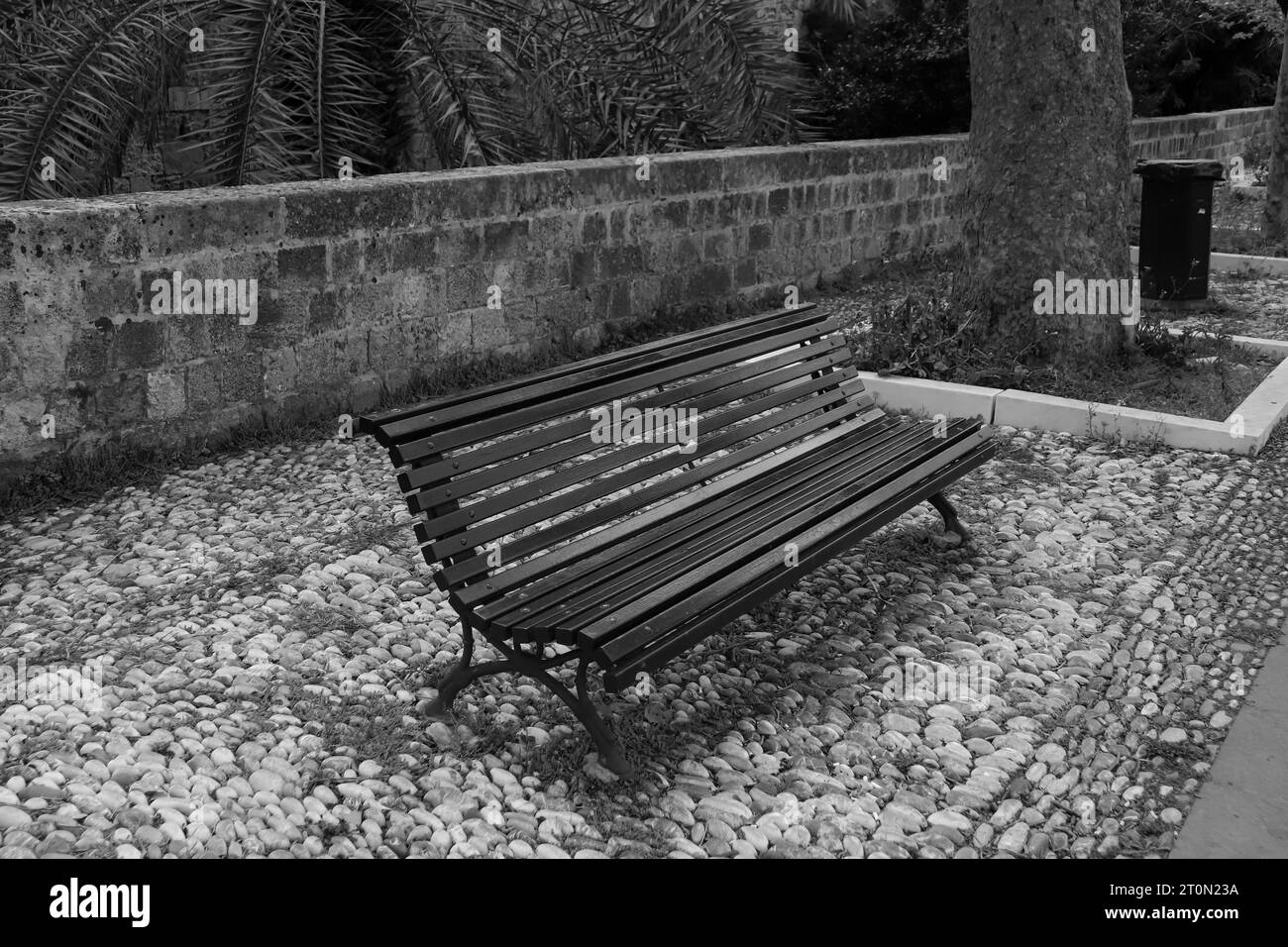 Empty city park wooden bench along Rhodes Old Town path in black and ...