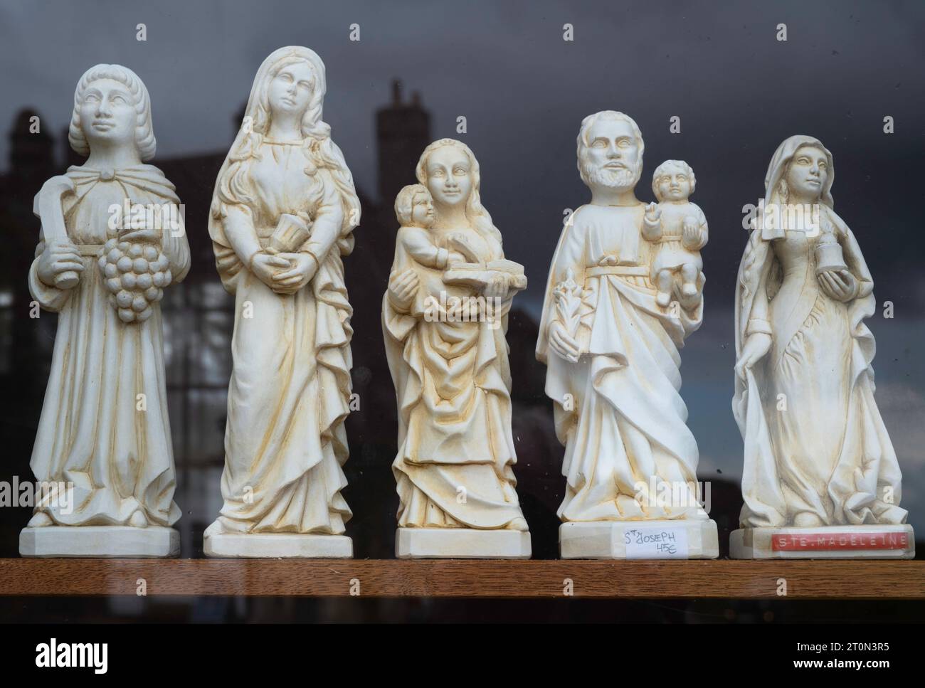 Small statues or figurines of saints in a souvenir window next to the ...