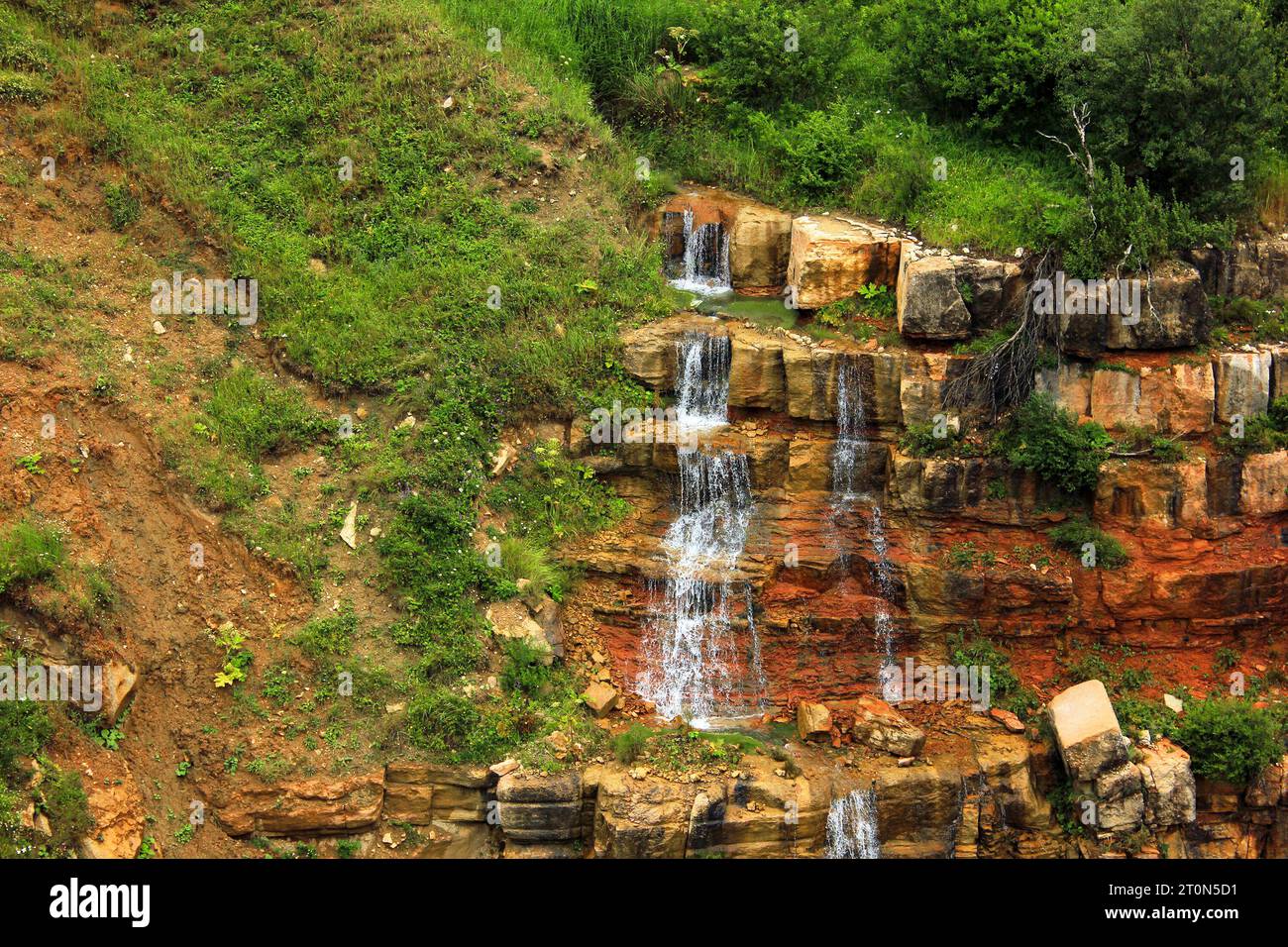 Beautiful waterfall with red mountains in the gorge. The road to the ...