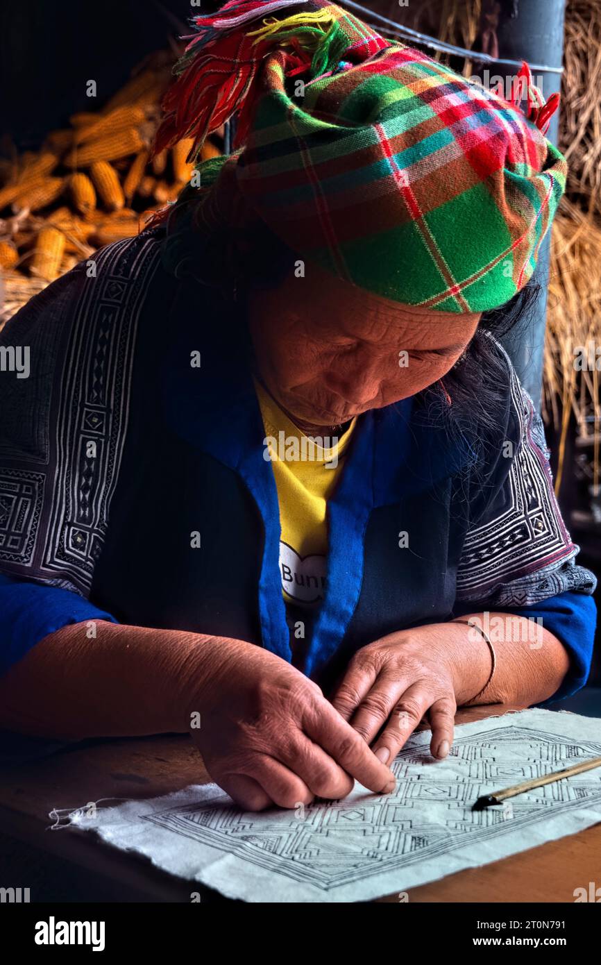 A Flower Hmong woman draws a pattern for her traditional embroidery, Mu ...
