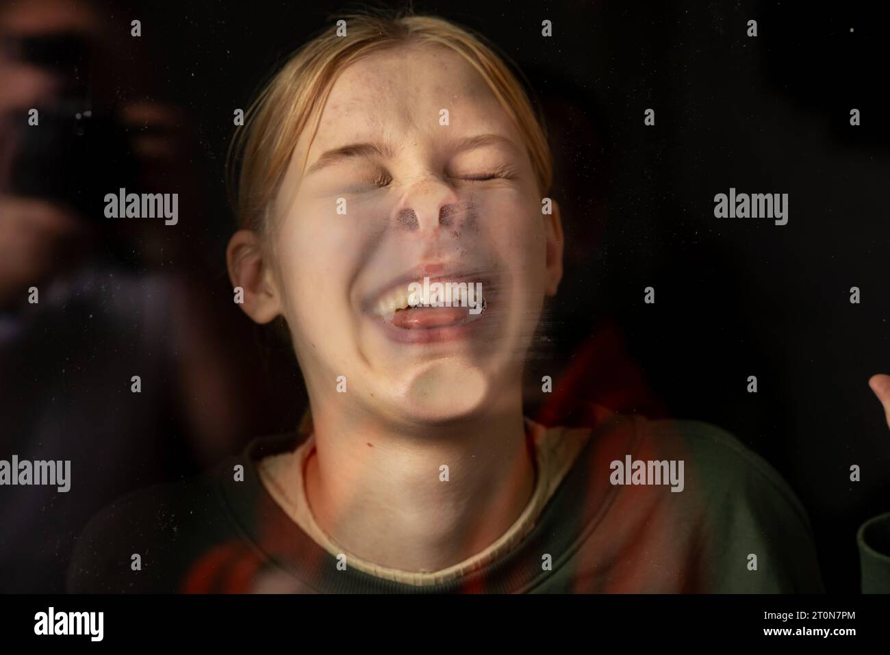 Portrait of a teenage girl through her face pressed against the glass ...