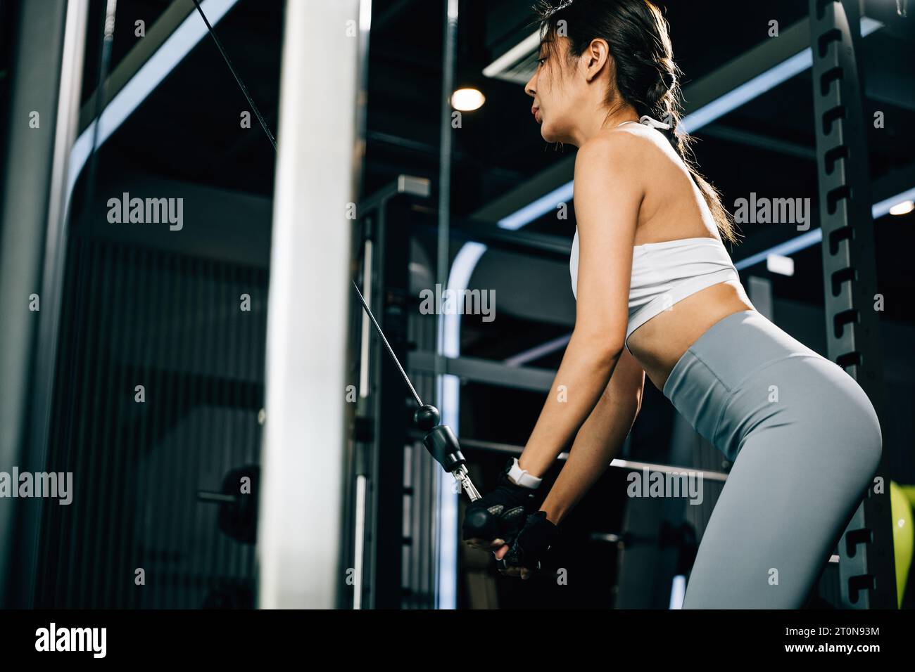 Slim and strong young woman working out on a pull-down weight machine ...