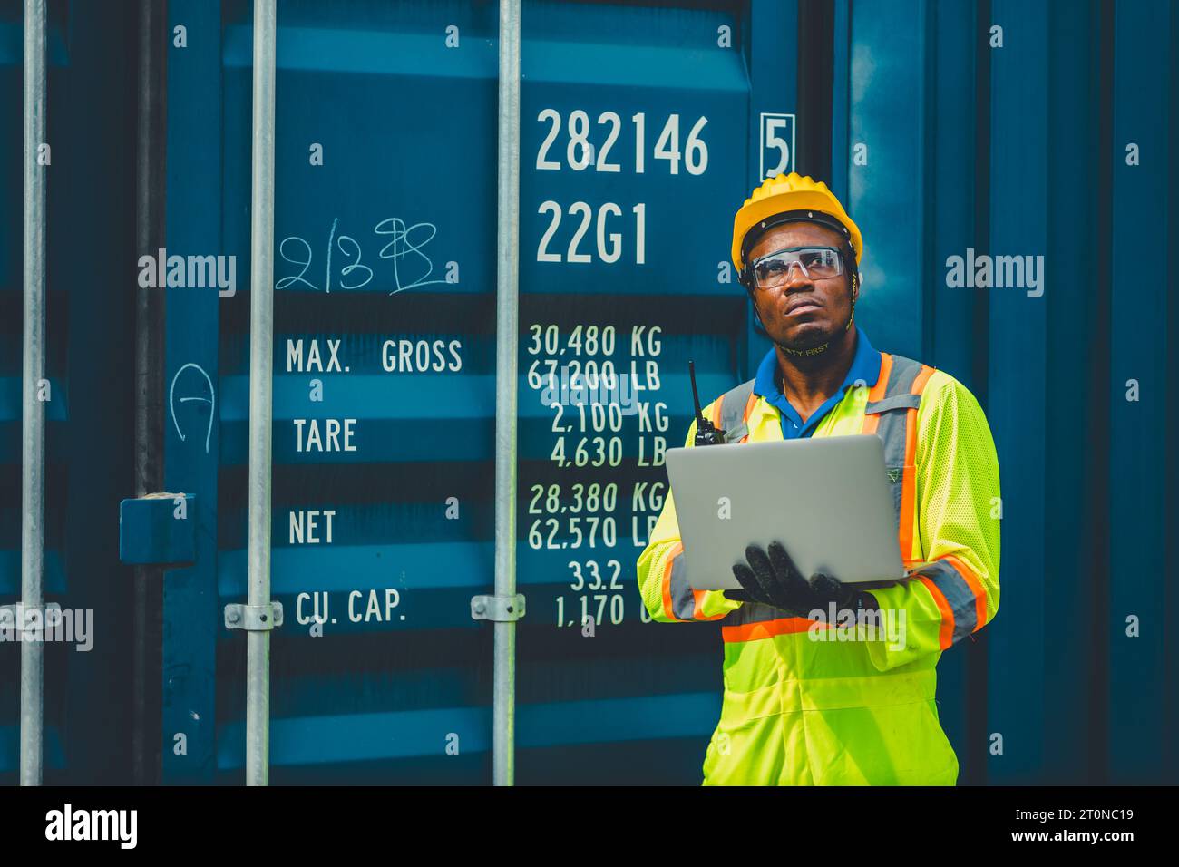 African male dock worker control loading containers cargo at warehouse container shipyard ...