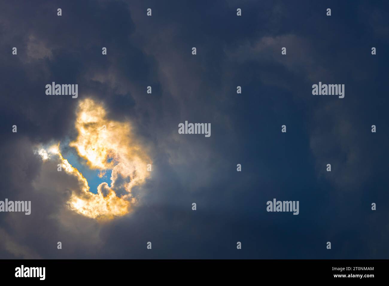 bright sunlight in a dark blue thundercloud. a gap in the dark sky ...