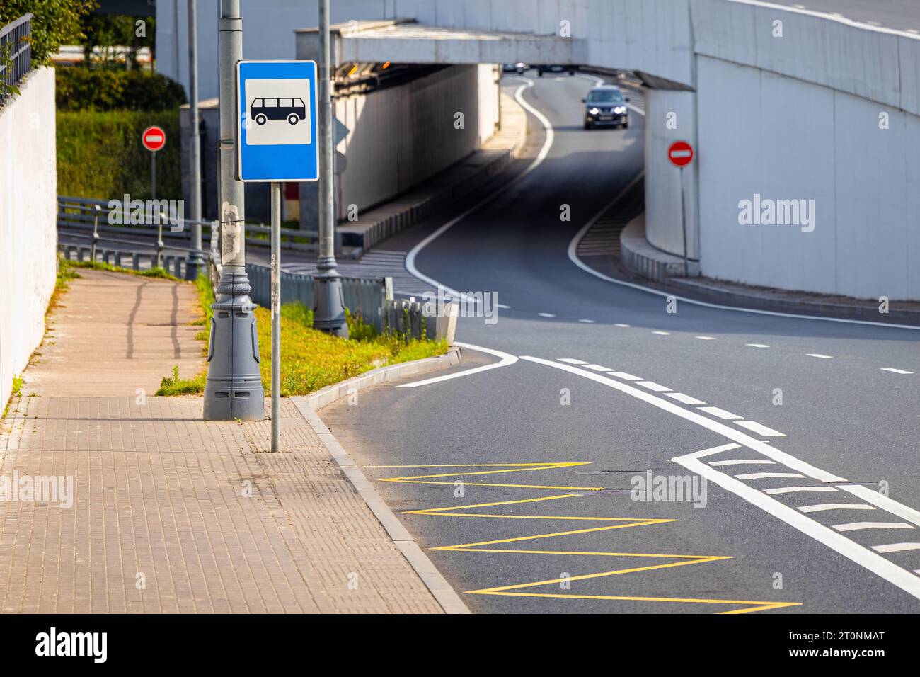 empty bus stop on the roadway in the city. bus stop sign. road markings ...