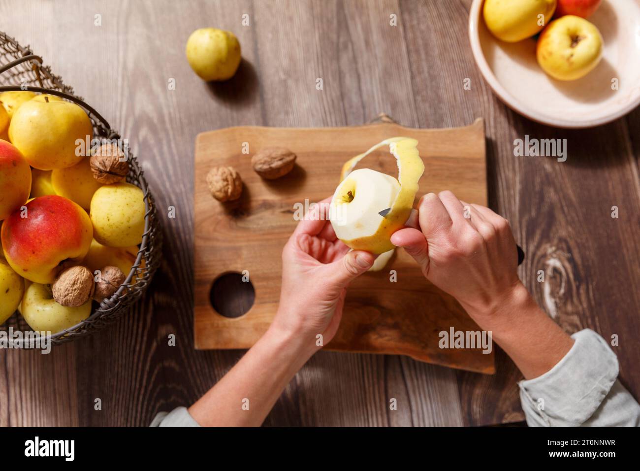 Human hands peeling an apple on a kitchen with a knife over a wooden ...