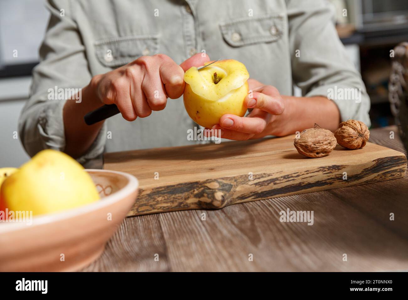 Human hands peeling an apple on a kitchen with a knife over a wooden ...