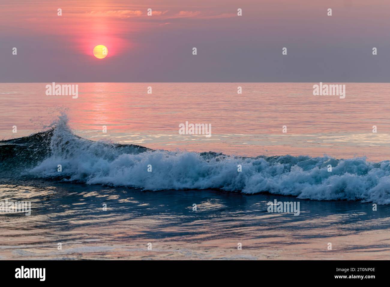 The summer sun rises over the Atlantic Ocean infusing the coastline ...