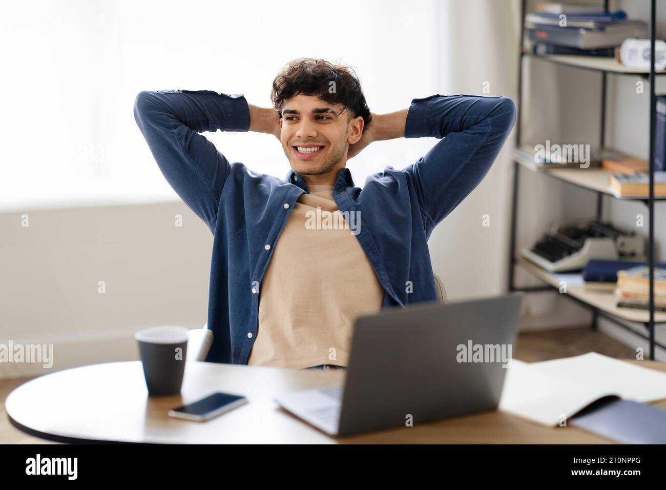 Smiling Middle Eastern Young Man Reclining In Chair At Workplace Stock ...