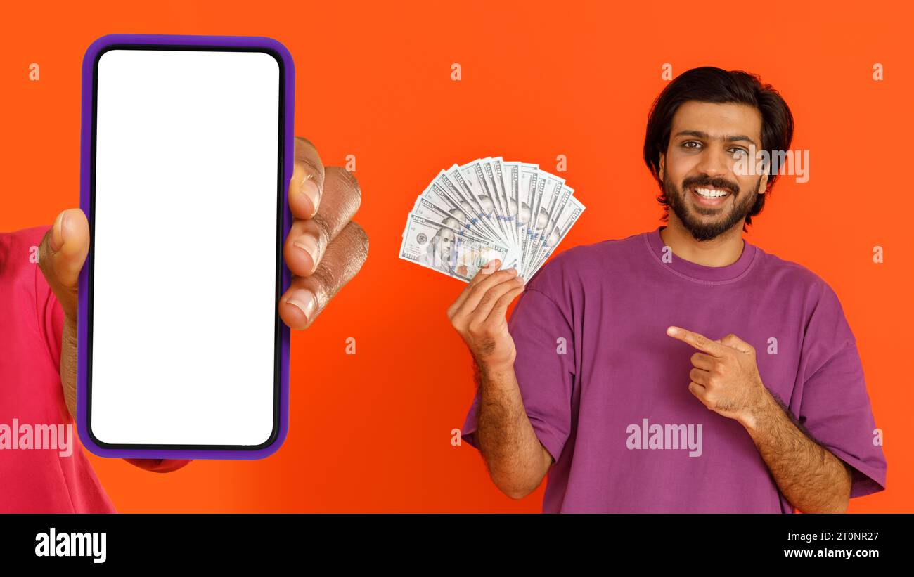 Smiling indian young man pointing finger at many money, near hand with ...