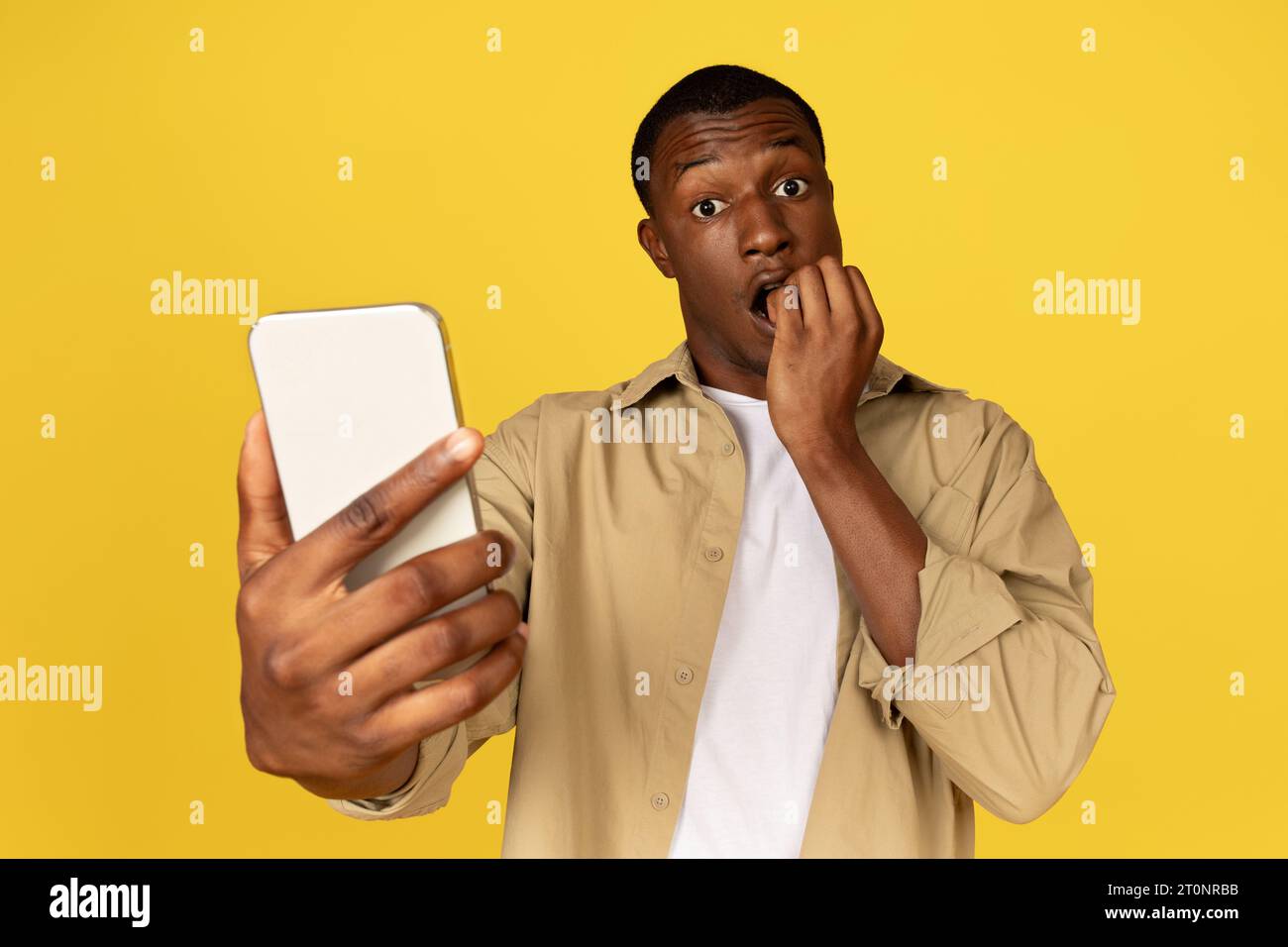Shocked scared millennial african american guy in casual bite fingers ...