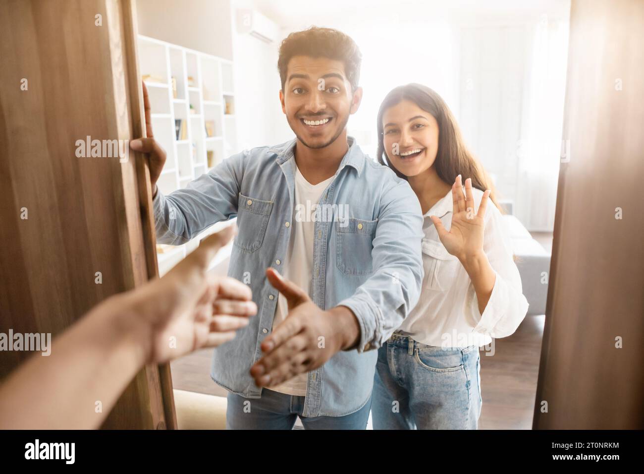 Hello. Happy indian spouses meeting somebody standing near opened door ...