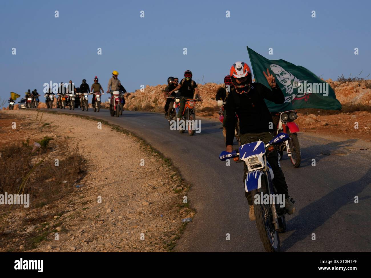 Hezbollah supporters ride their motorcycles with a flag that shows the ...